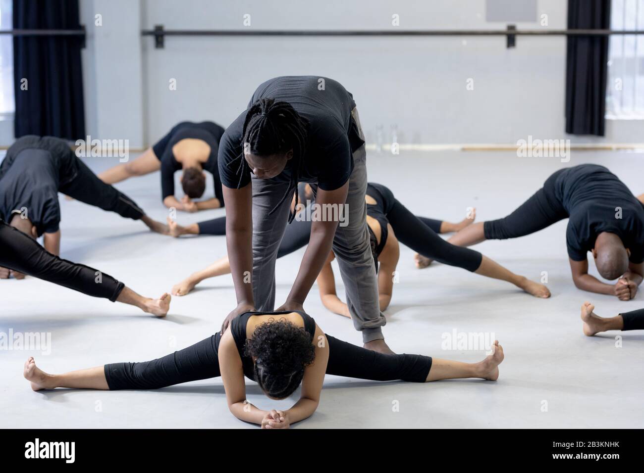 Male dancer helping modern dancers stretching up in a studio Stock ...