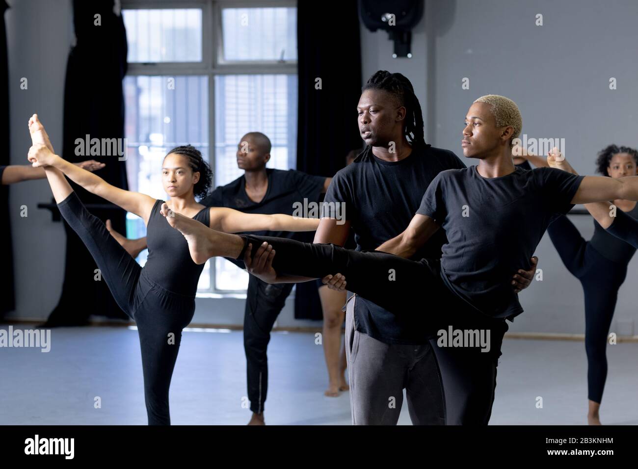 Male dancer helping modern dancers practicing a dance routine in a ...