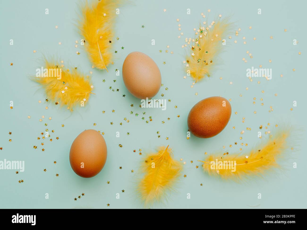Simple brown three unpainted eggs and a yellow fluffy bird's feather on ...