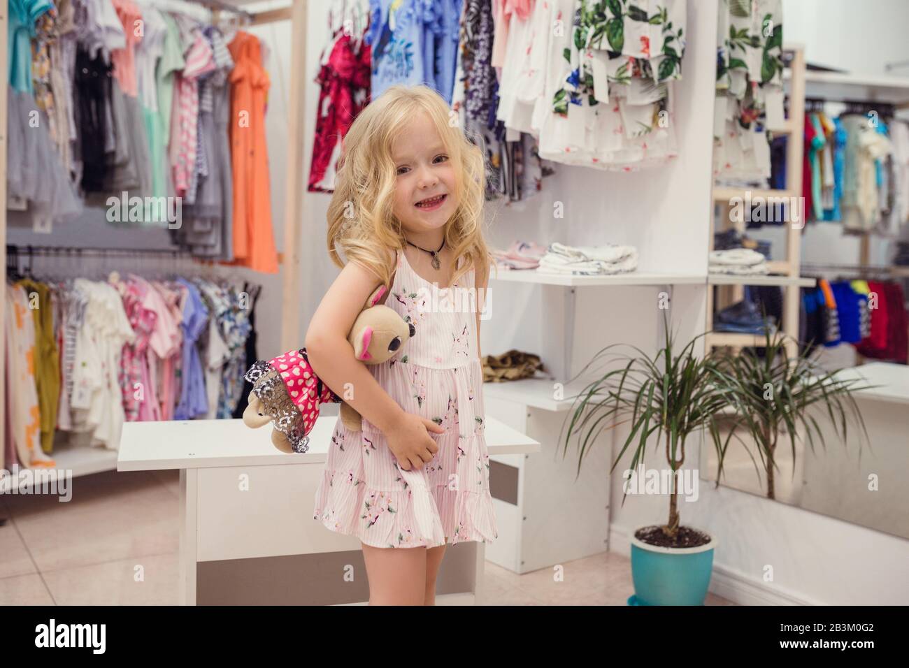 Cute little girl on shopping chooses summer clothes. discounts. little ...