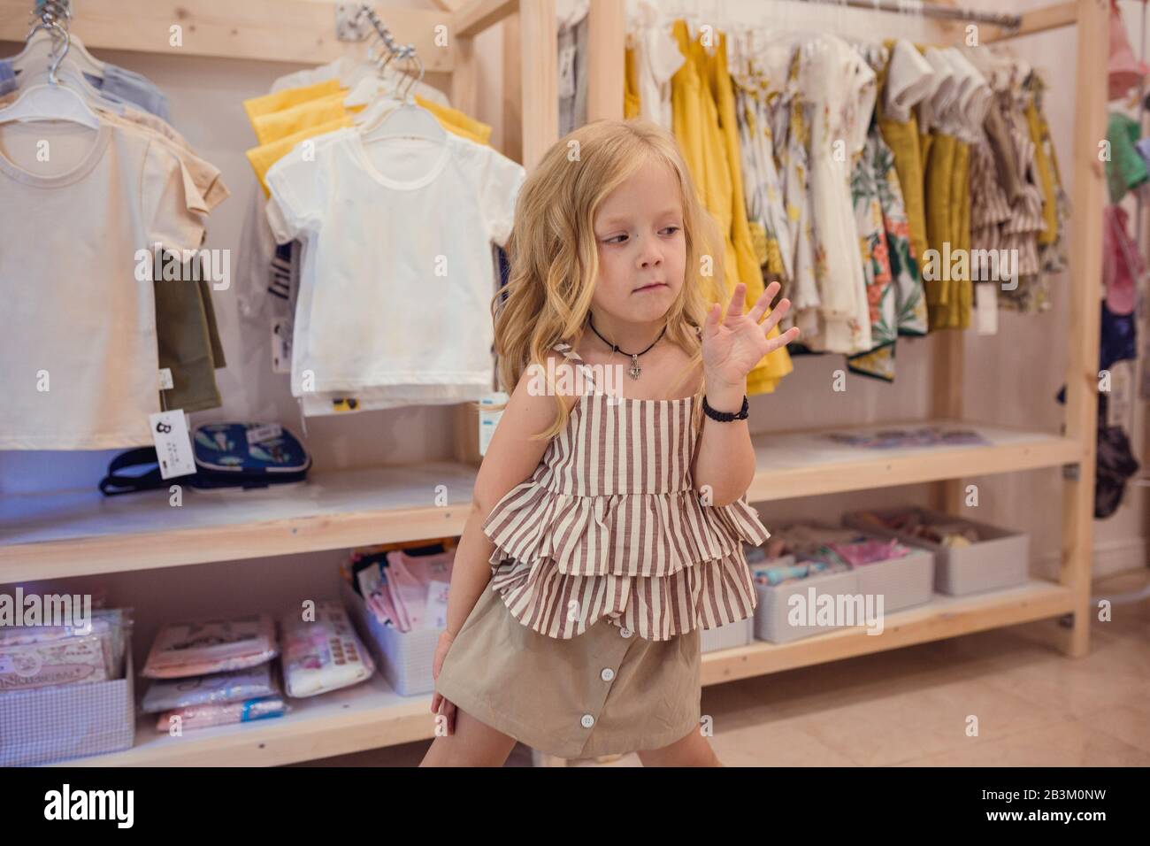 Cute little girl on shopping chooses summer clothes. discounts. little ...