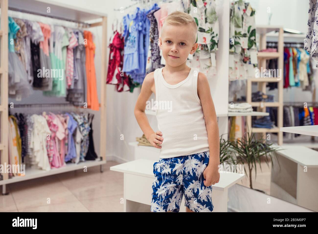 The boy tries on clothes in the childrens clothing store. Little ...