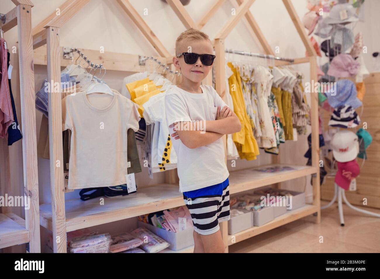 The boy tries on clothes in the childrens clothing store. Little ...