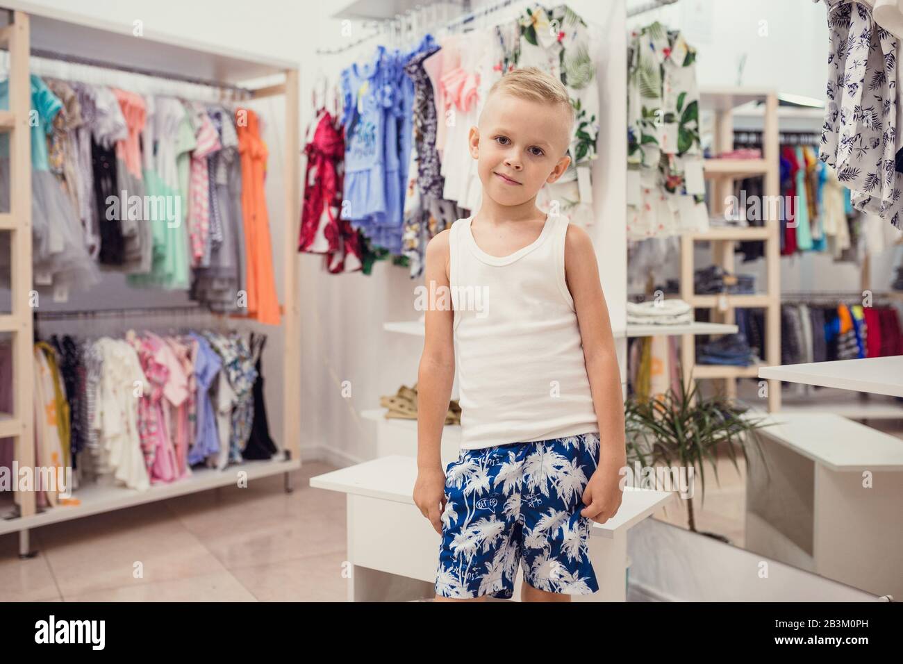 The boy tries on clothes in the childrens clothing store. Little ...