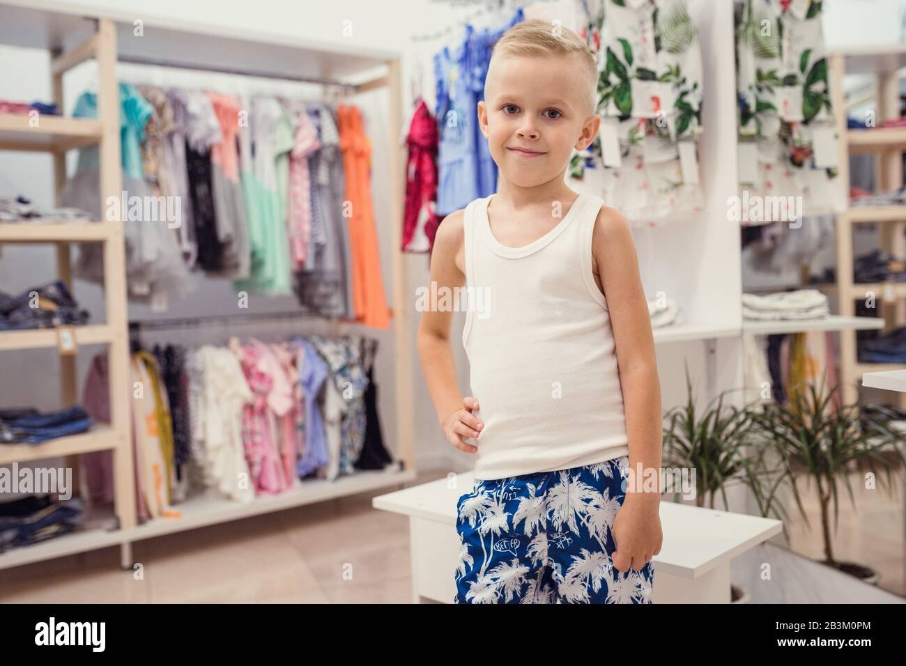 The boy tries on clothes in the childrens clothing store. Little ...