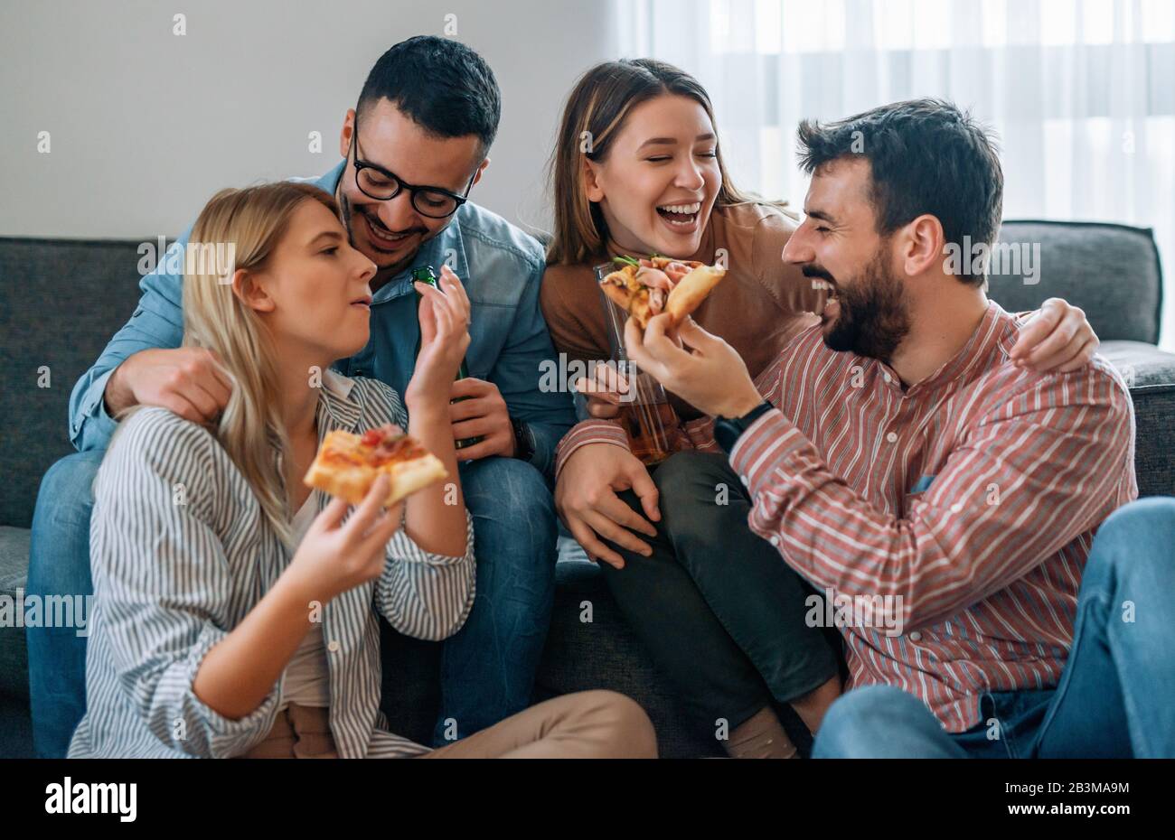 Group of cheerful friends eating delicious pizza.Happy friends having ...