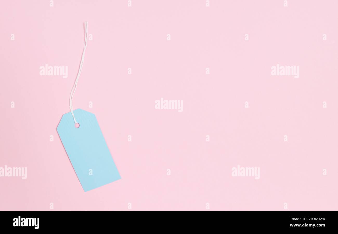 Blue paper tag for notes on a pink background. View from above ...