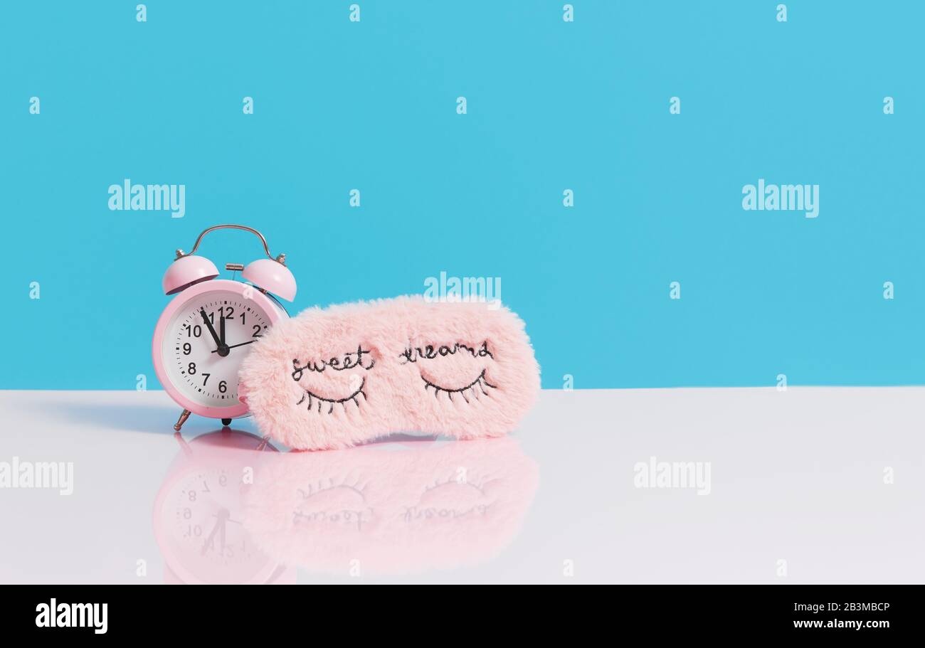 Sleep optimization. Pink fluffy mask for sleeping and a pink alarm ...