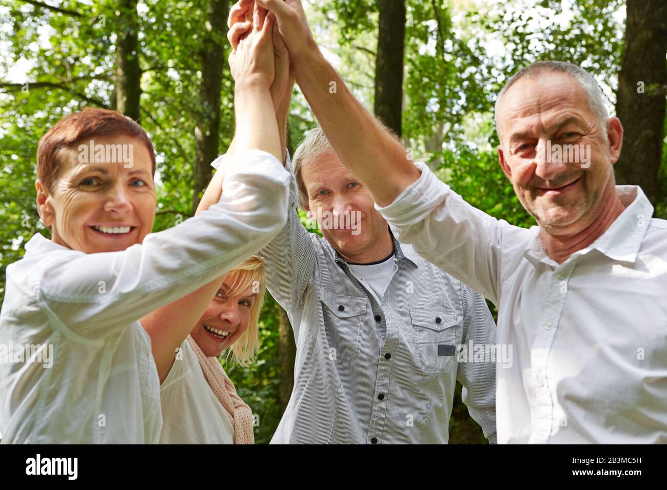 A laughing team of seniors gives themselves high five to motivate them ...