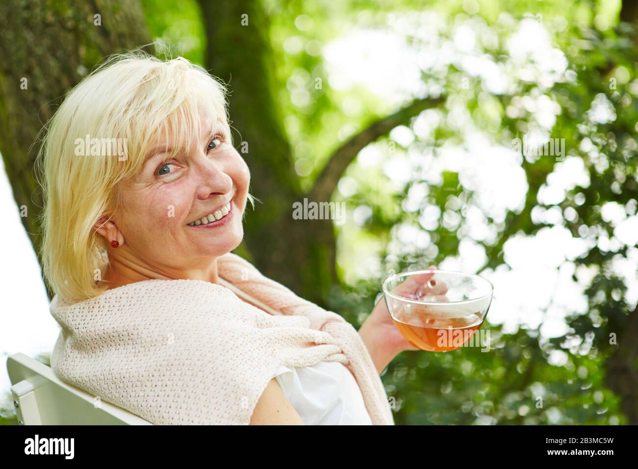 Old smiling woman relaxing while drinking tea in the garden Stock Photo ...
