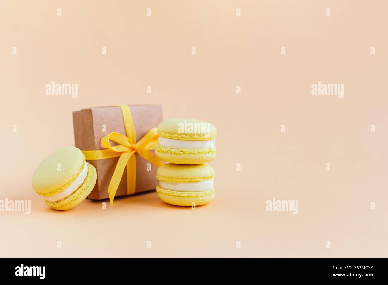 Yellow macarons with gift box on a peach pastel background. Lemon ...