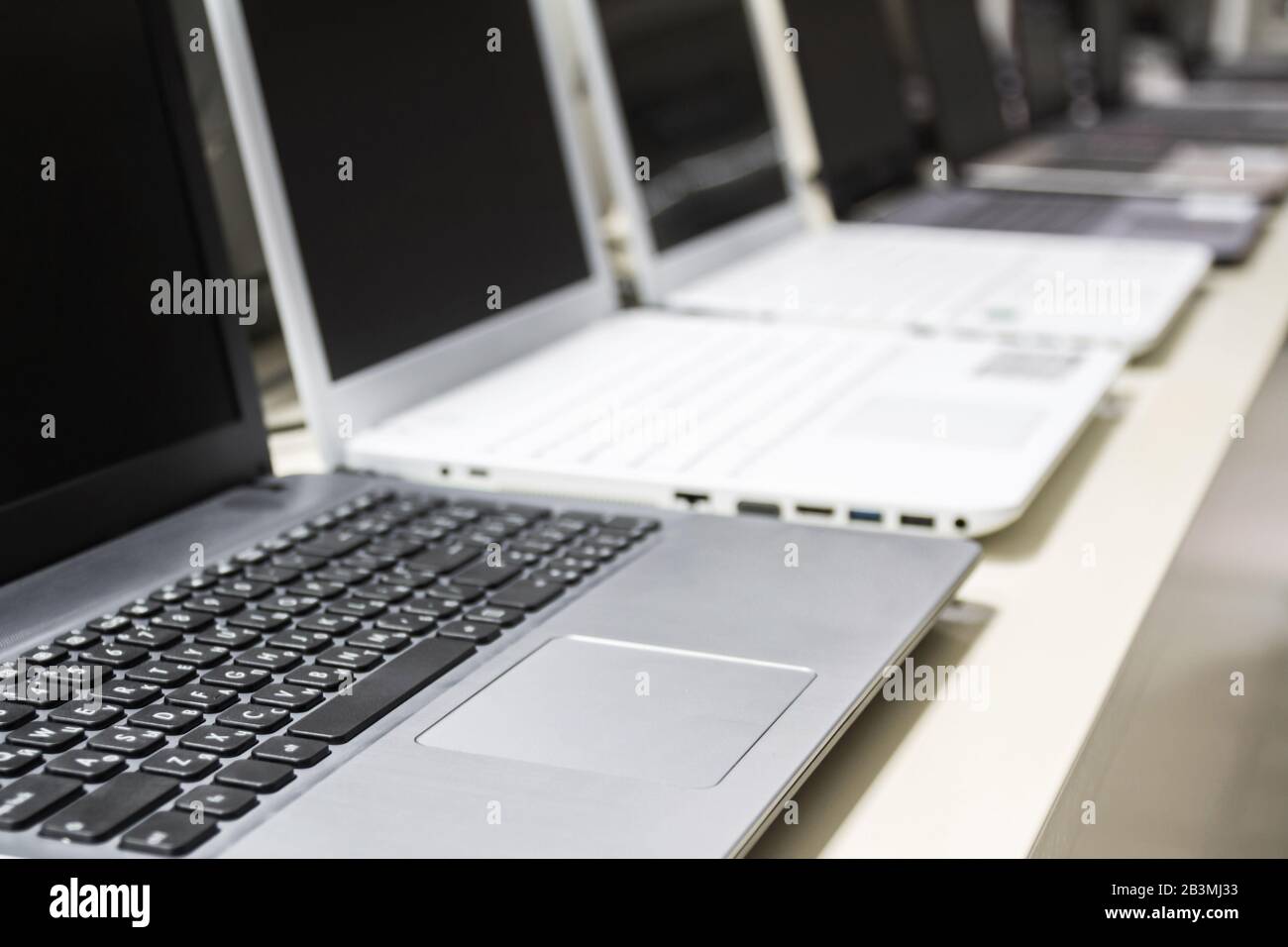 A row of laptops in computer shop. Closeup, selective focus Stock Photo ...