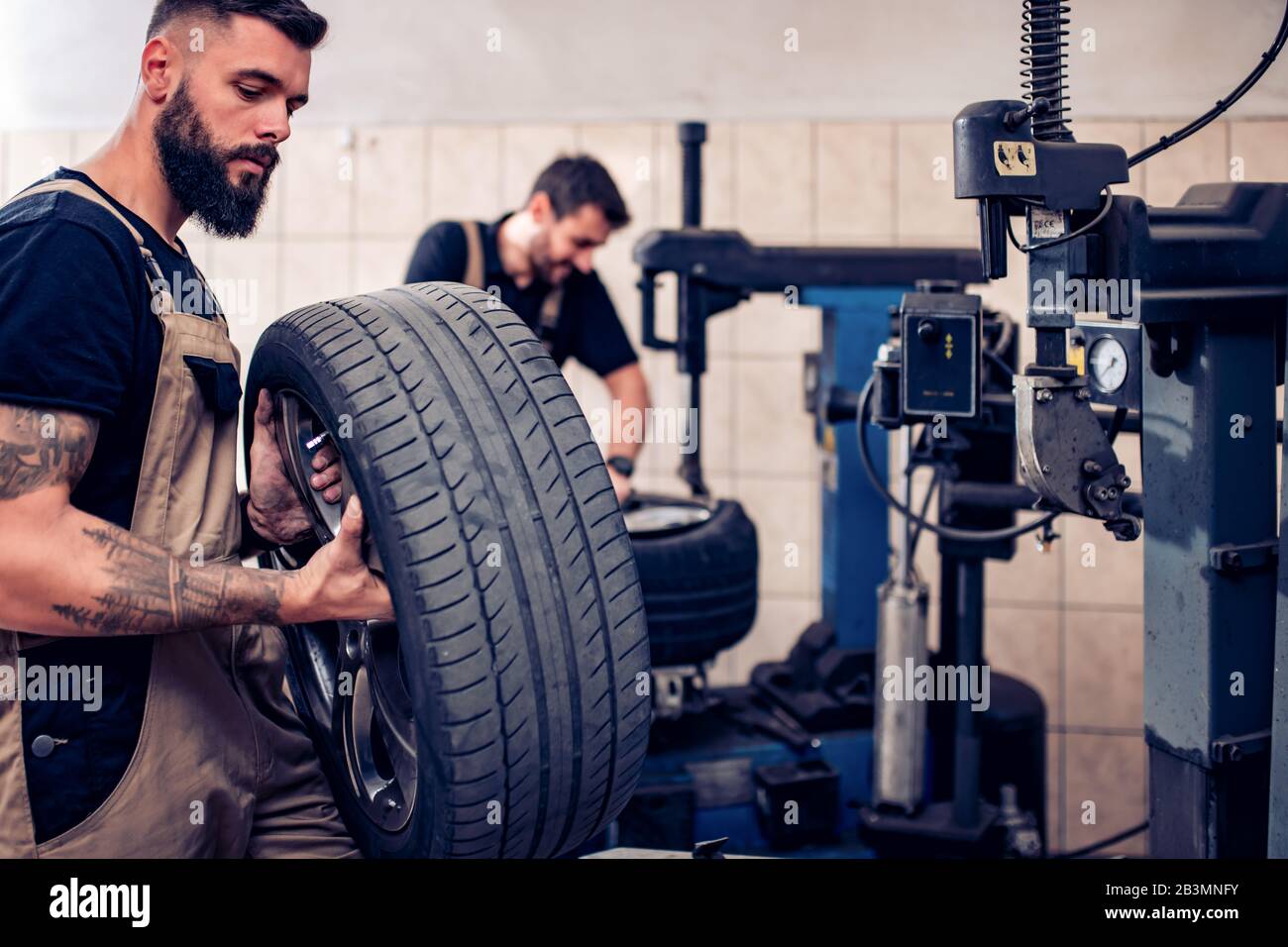 Teamwork.Mechanic holding a tire at the repair garage. Replacement of ...