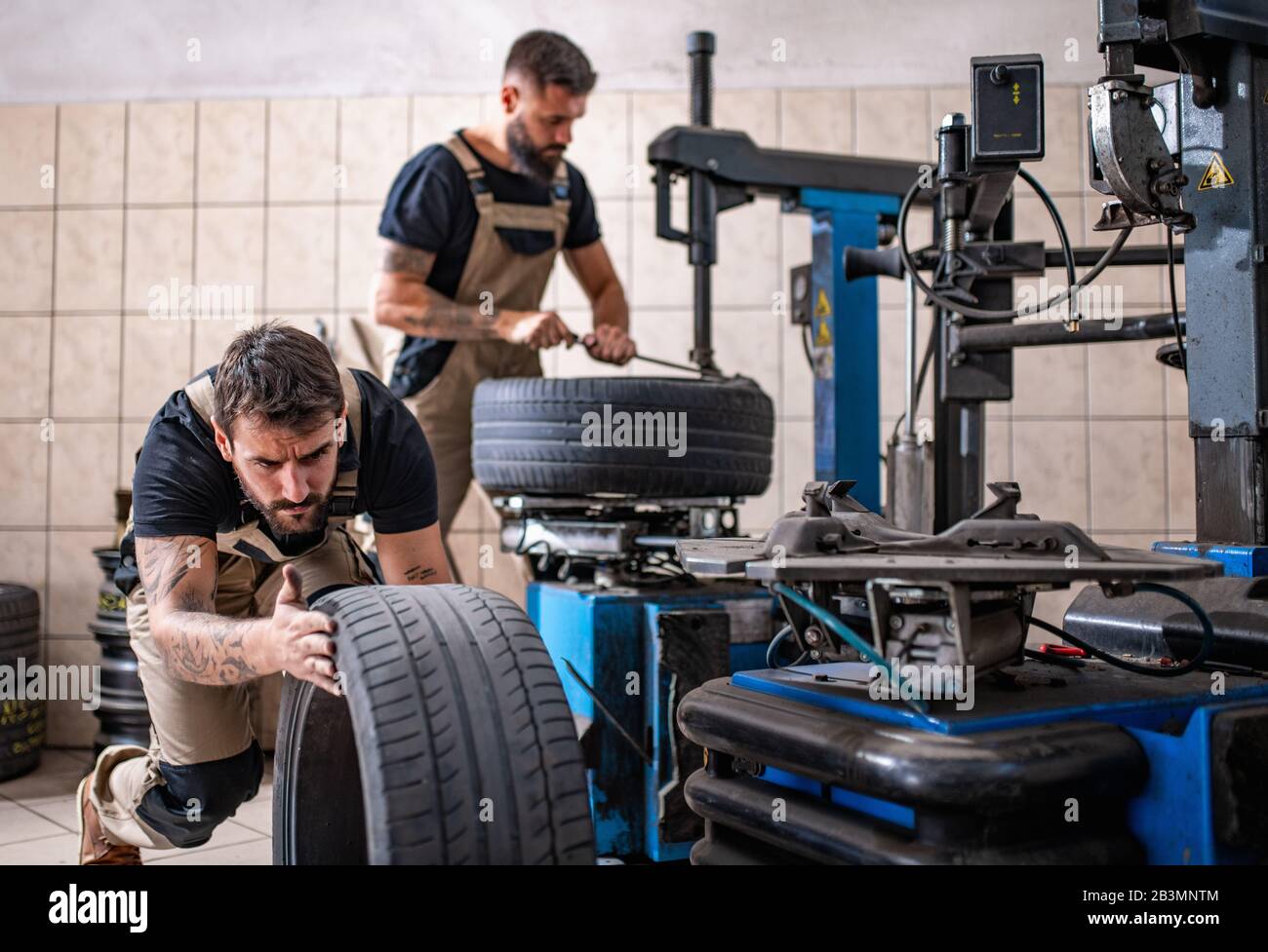 Teamwork.Mechanic holding a tire at the repair garage. Replacement of ...