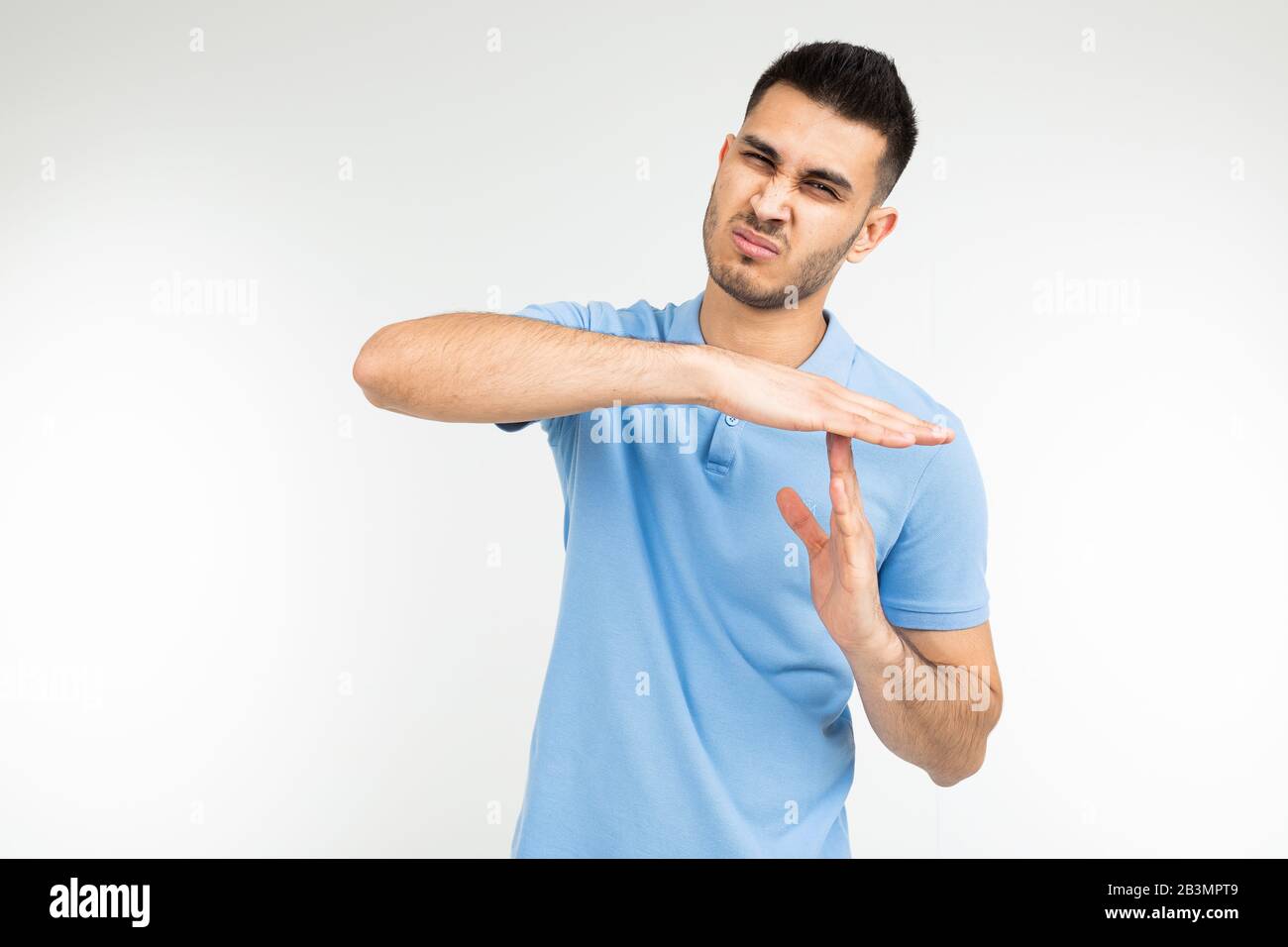 a man in a blue T-shirt shows the letter t with his hands against a ...