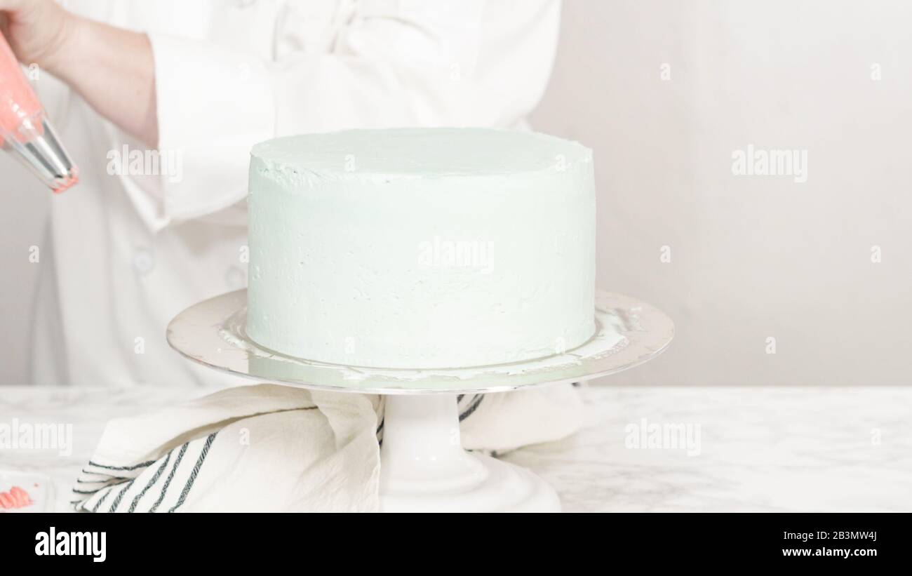 Piping buttercream rosettes on top of round three-layer vanilla cake ...