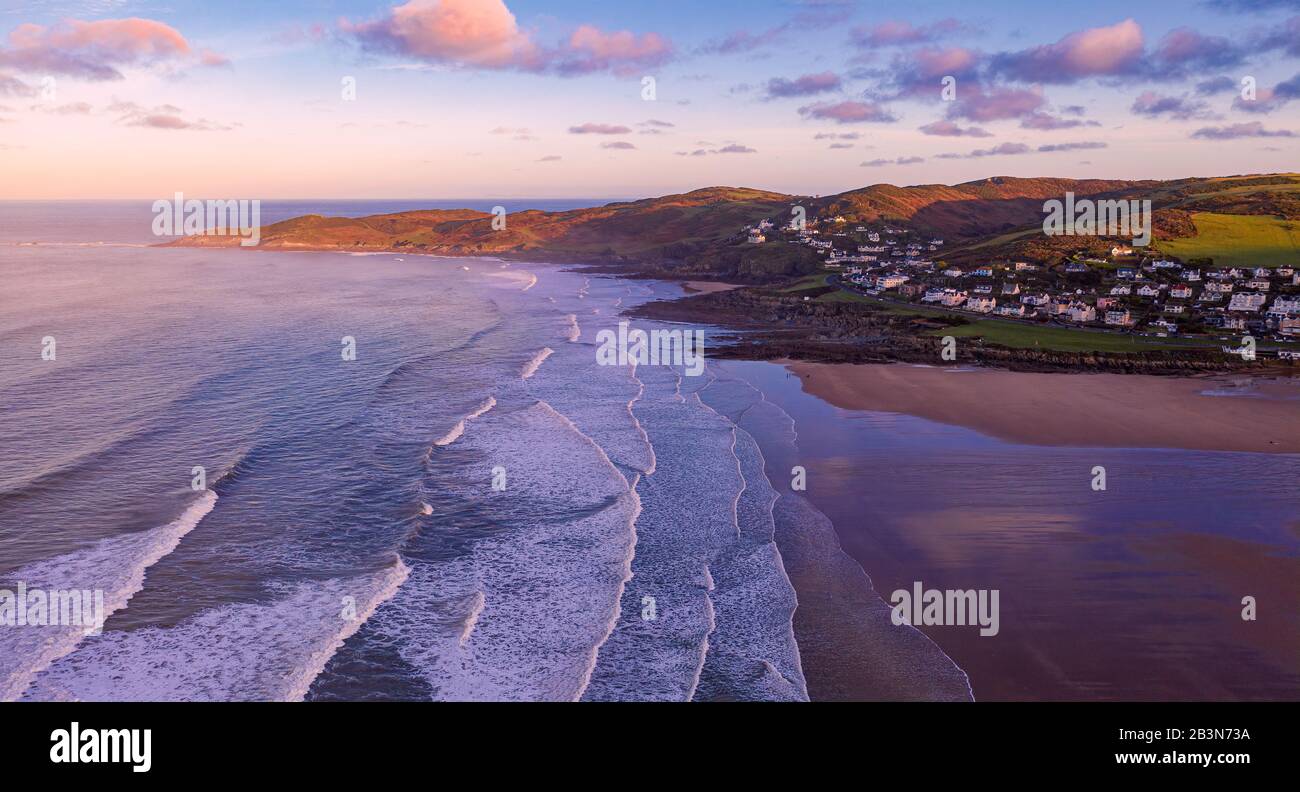 Aerial view of the town of Woolacombe and it's beach at dawn, waves ...