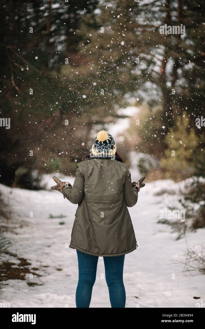 Back view of a girl standing in snowing forest. Back of a woman ...