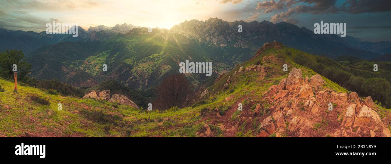 Panorama mountain range and valley at sunset, the sun just visible over ...