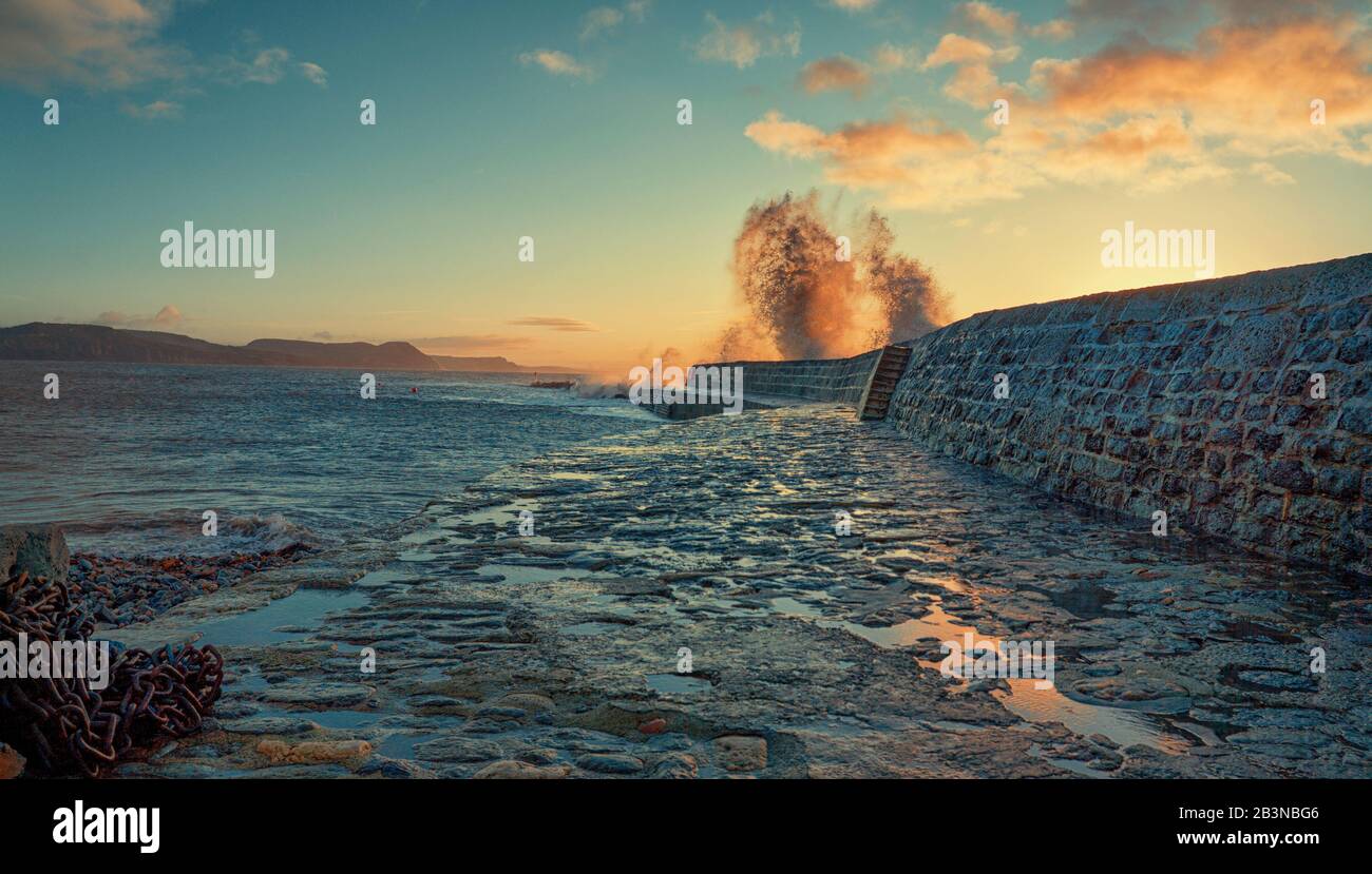 Waves break over the harbour wall of the cobb in Lyme Regis the ...
