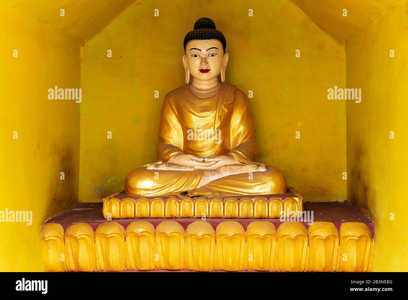 A gold-coloured Buddha statue in a yellow alcove in a temple opposite ...
