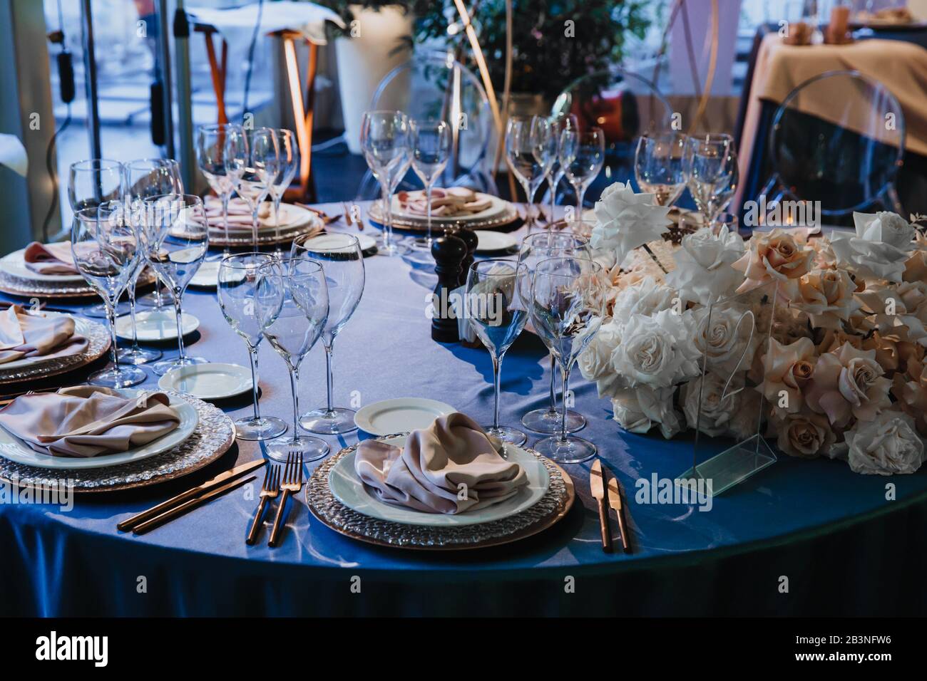 Glasses, forks, knives, plates on a table in restaurant served for ...