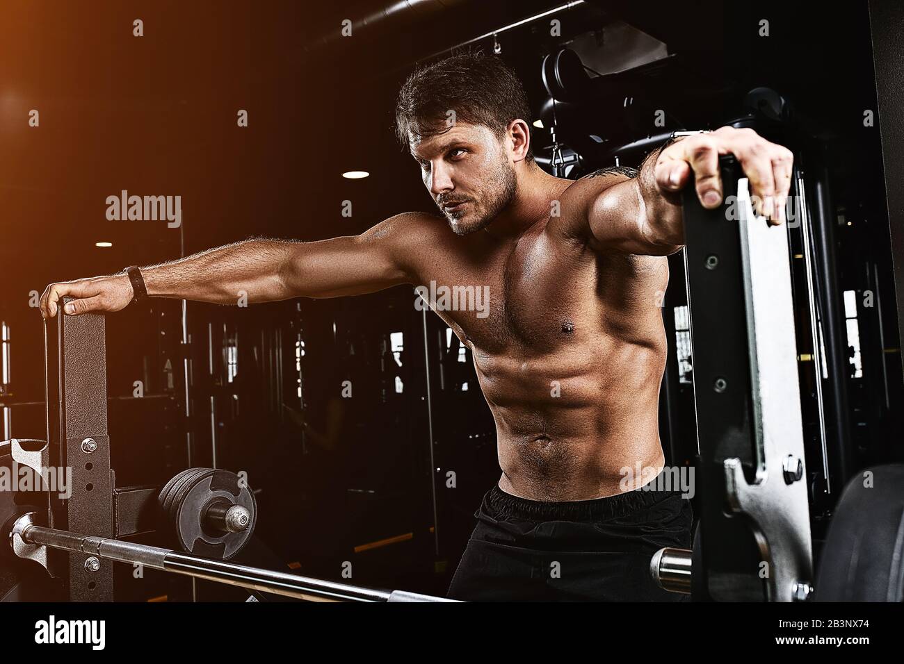 Young muscular man lifting a barbell bench press in the gym. Beautiful ...
