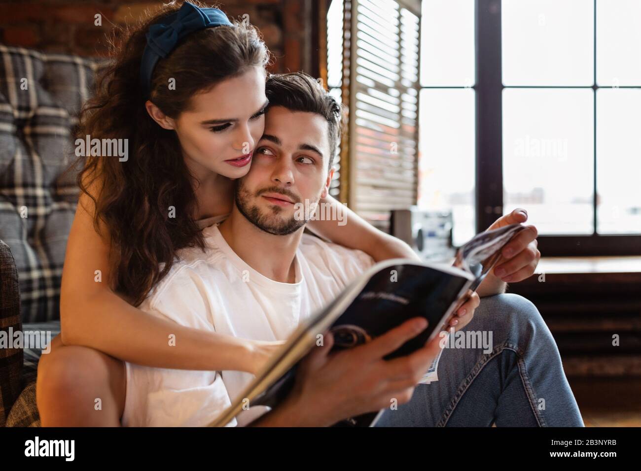 Portrait of a charming young couple at home. Woman is embracing her ...