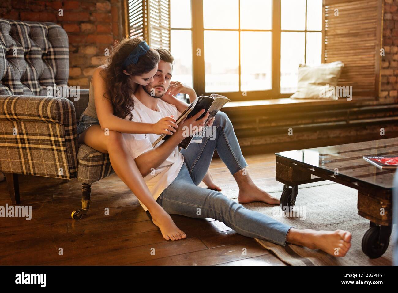 Portrait of a charming young couple at home. Woman is embracing her ...