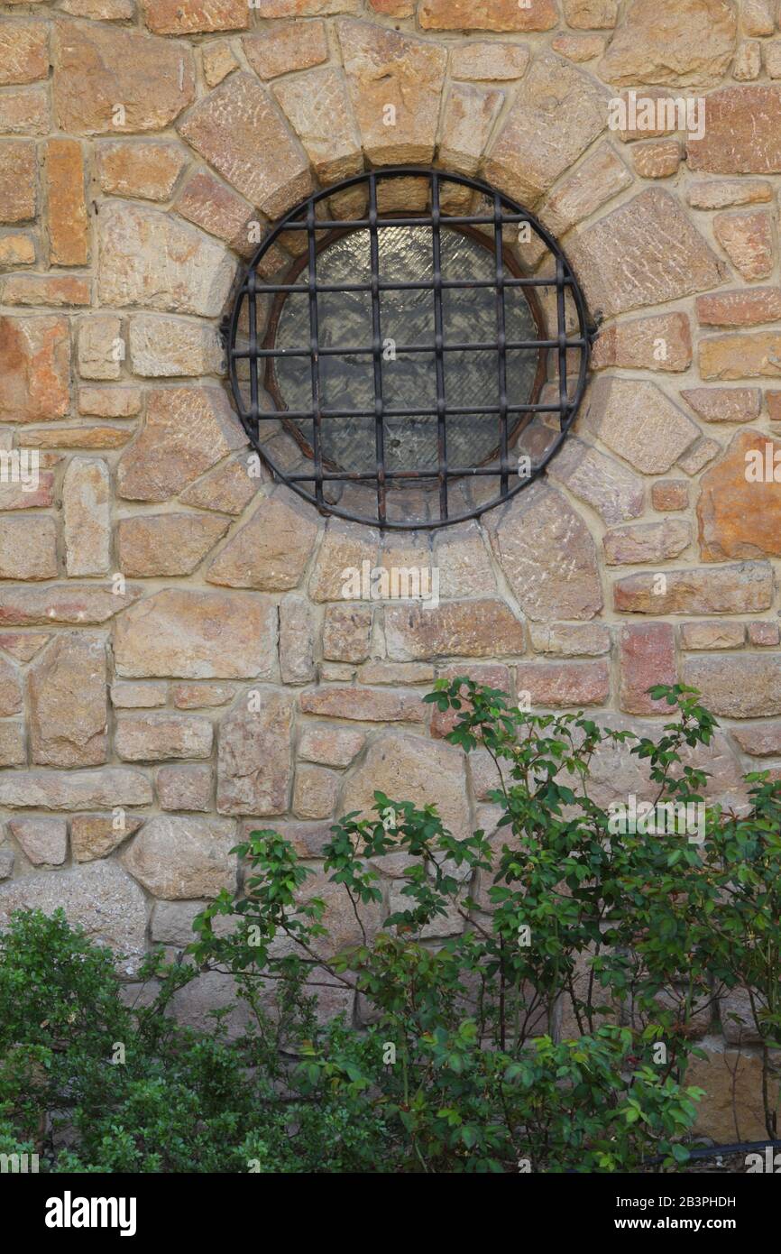 Medieval stone wall with round window with plant Stock Photo - Alamy