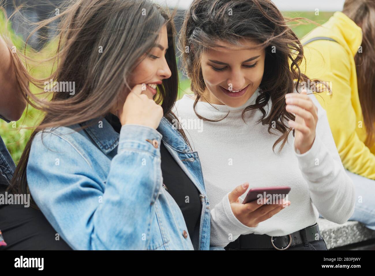 Two young women using mobile phone outdoors Stock Photo - Alamy