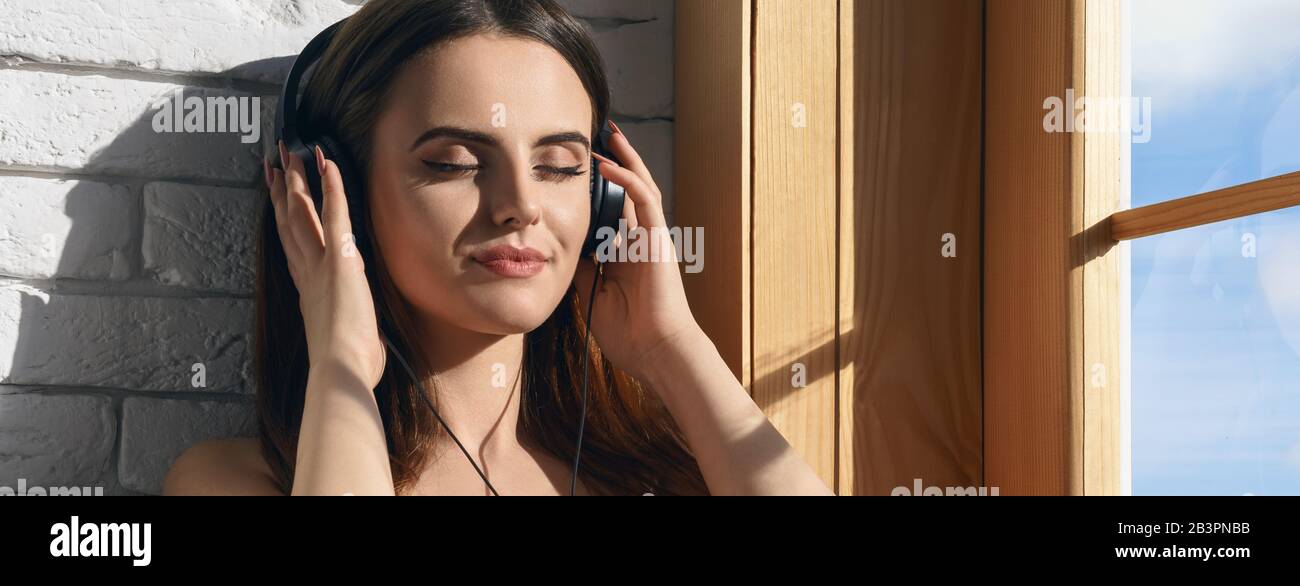 Wide shot of a pretty girl enjoying listening to music under sun light ...