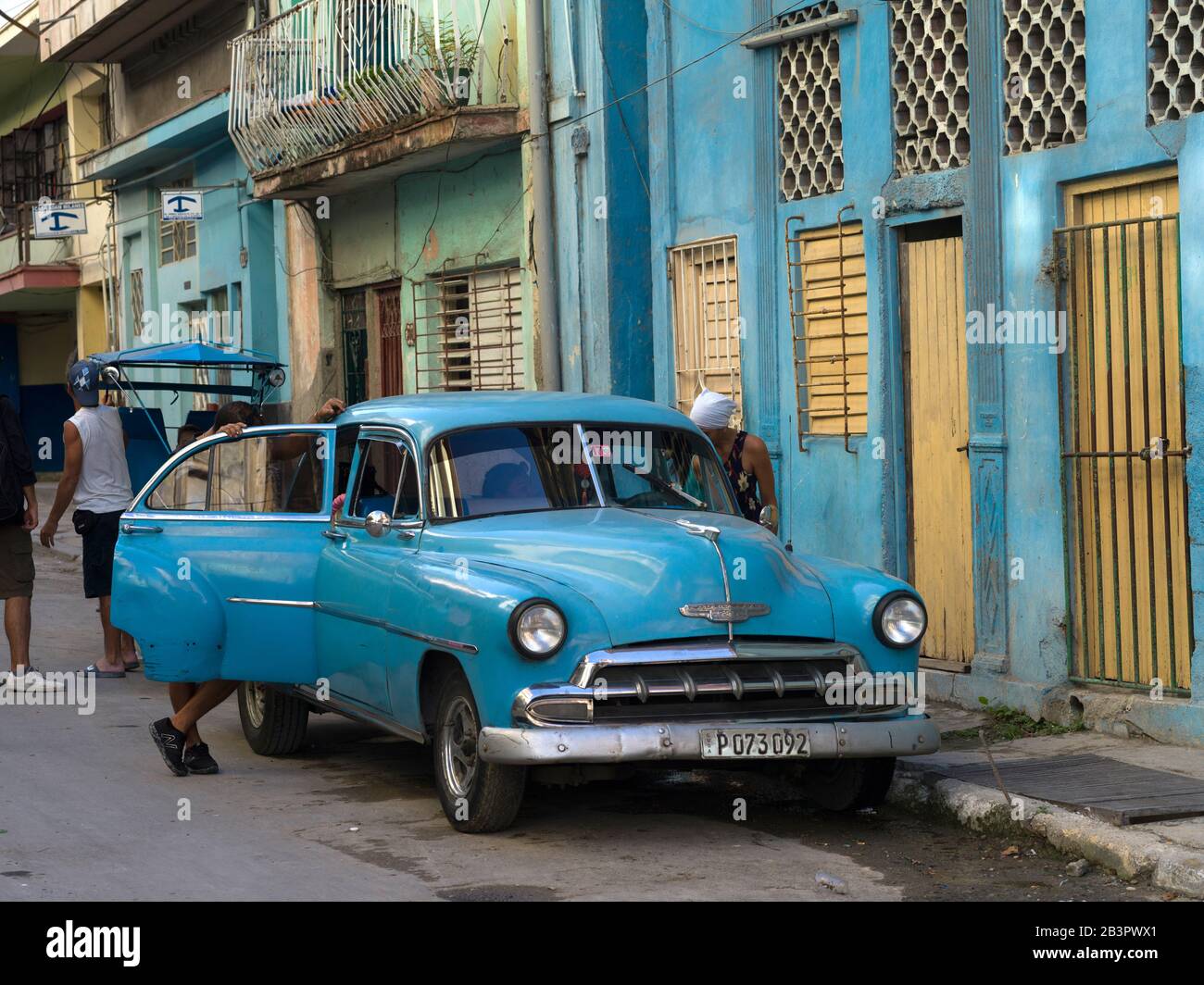 People standing near a car parked outside building, Havana, Cuba Stock ...