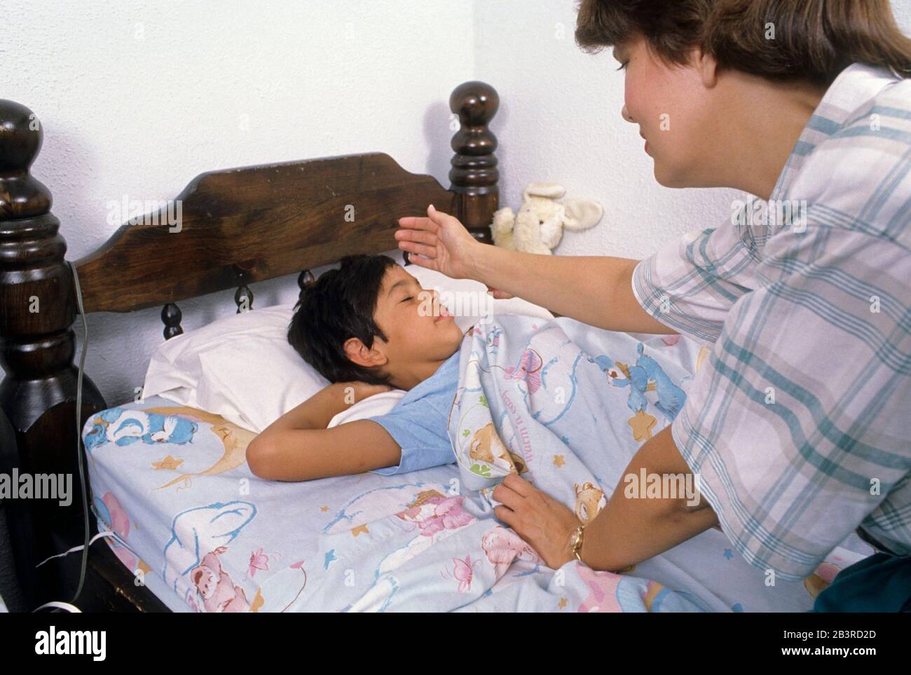 Woman tucking son into bed hi-res stock photography and images - Alamy