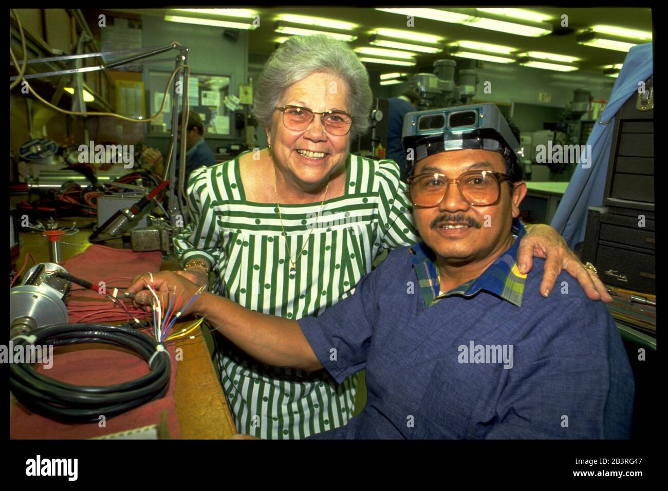 Female owner of small manufacturing business poses with male Hispanic ...