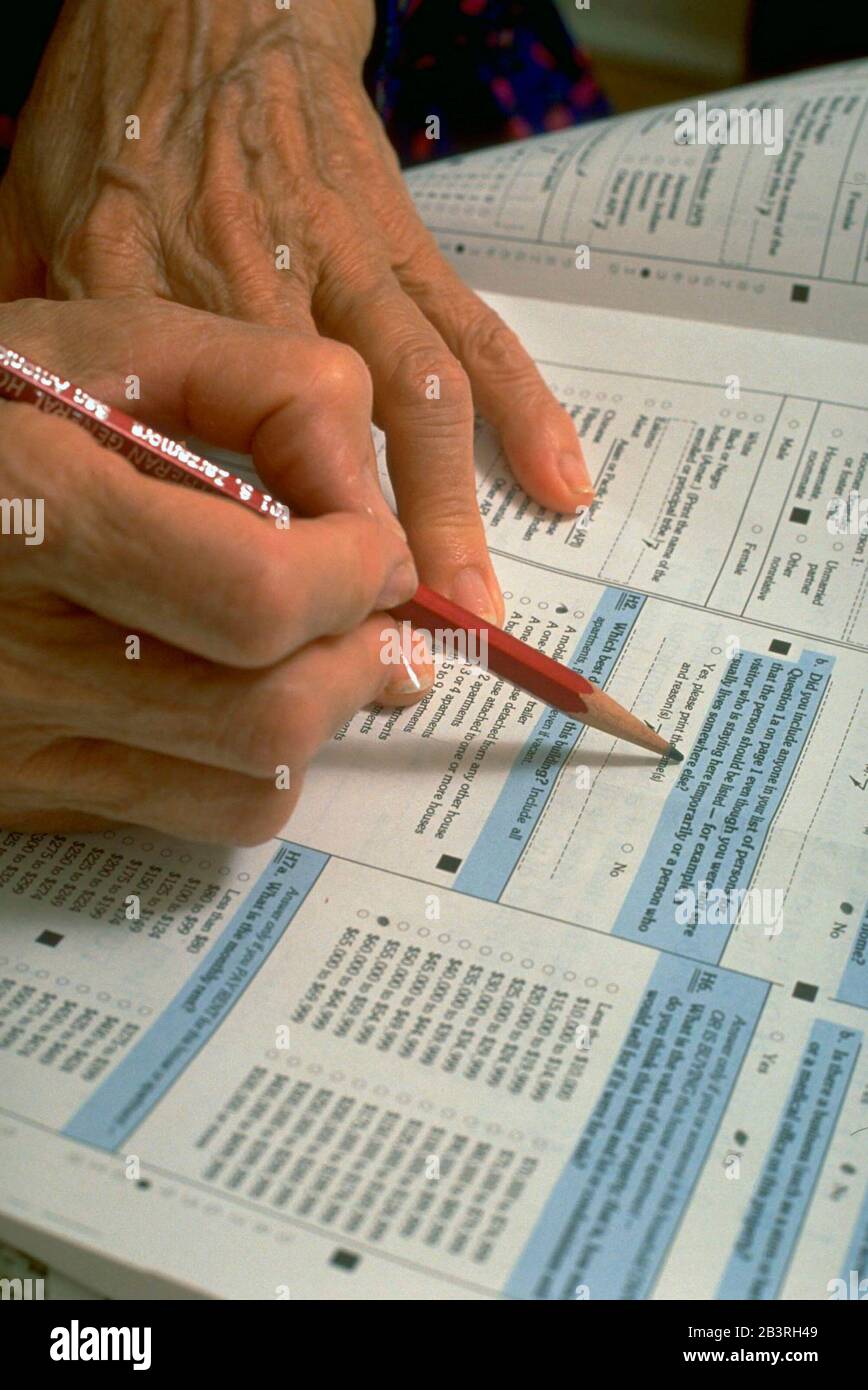 Elderly Hispanic woman using red pencil to fill out 1990 United States ...