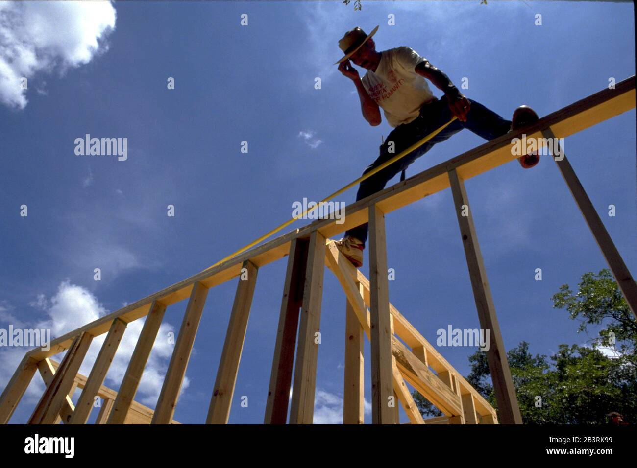 Austin Texas USA, circa 1990: Volunteer straddles house frame while ...