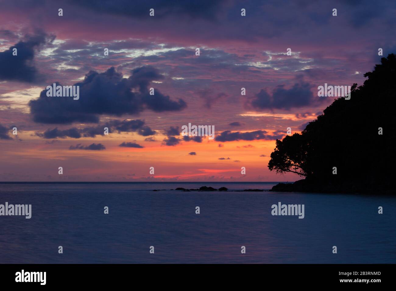 Vivid sunset sky waterscape and silhouette forest island background ...