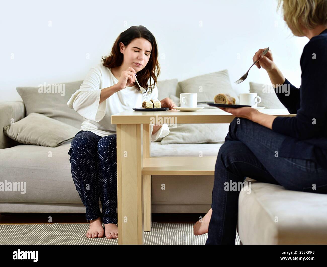 Two women sit eating and talking Stock Photo - Alamy