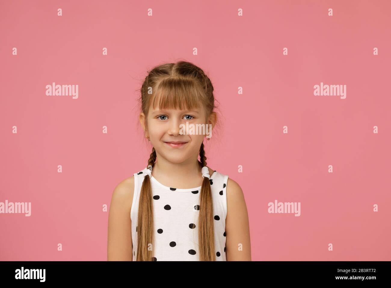 Cute smiling little child girl looking to camera on pink background ...