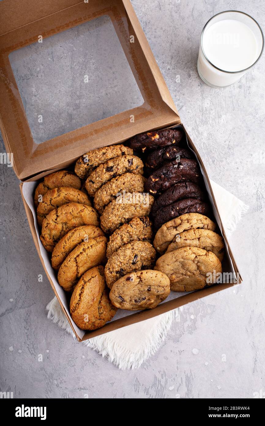 Box of assorted cookies freshly baked and packed to go and a glass of ...