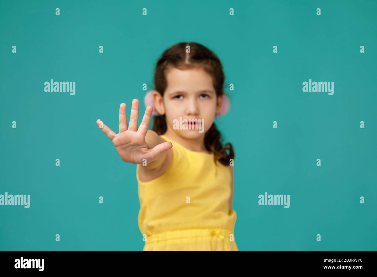 Cute little child girl making stop gesture on blue background. focus on ...
