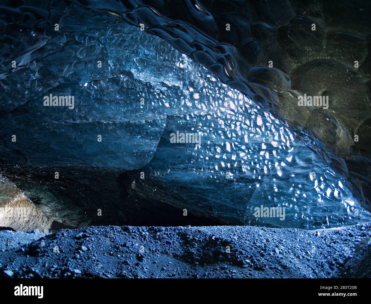 A thick layer of ice over the lava rock of a blue ice cave in Iceland ...