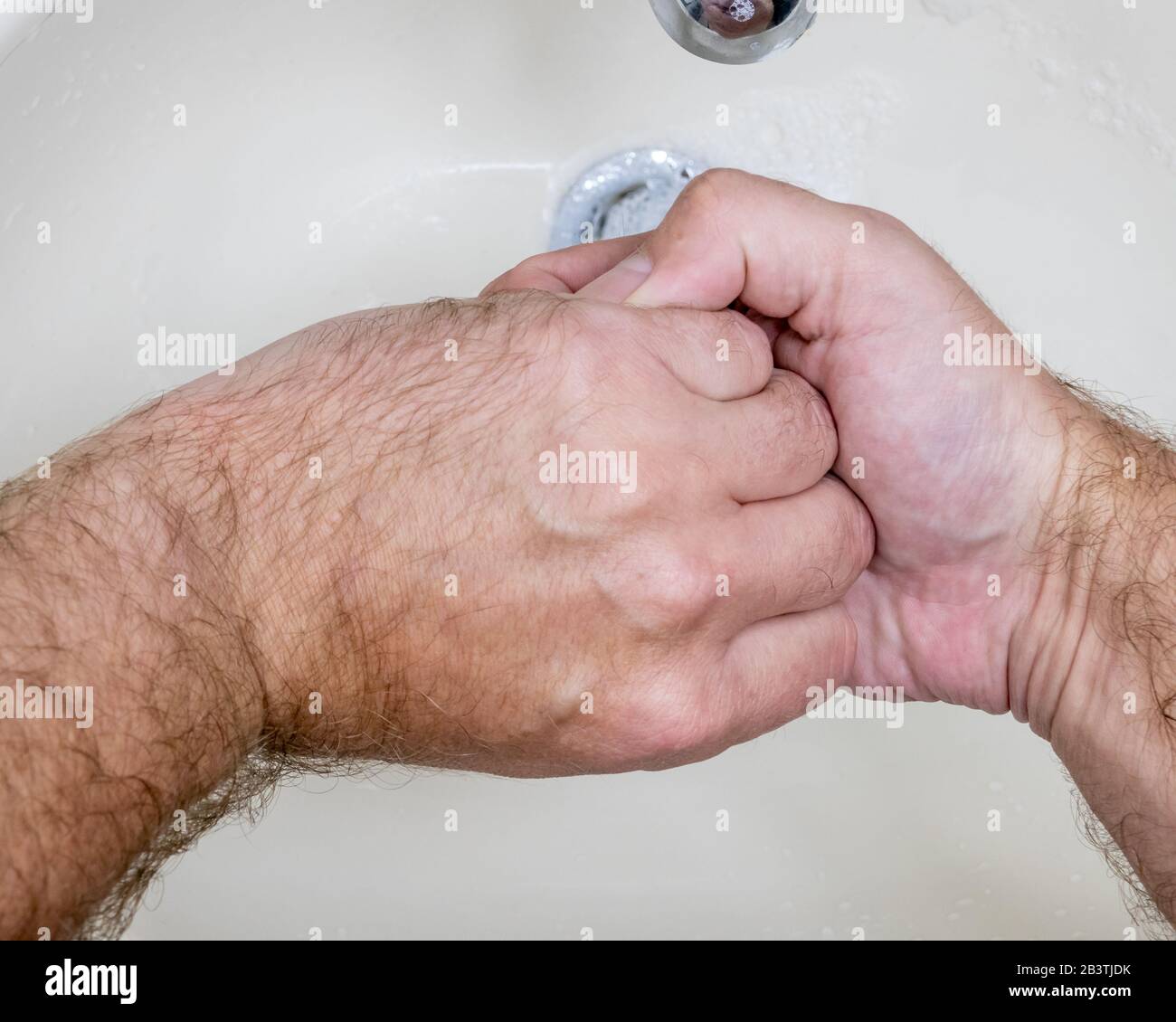 Man washing hands close-up from above, one of several handwashing steps ...