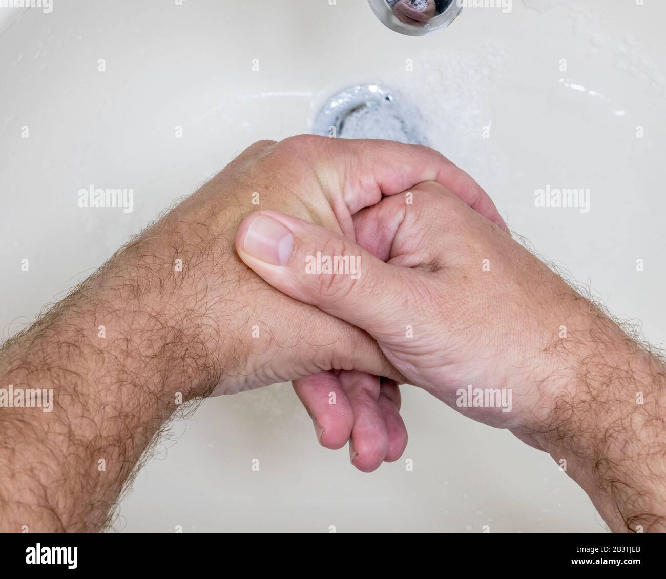 Man washing hands close-up from above, one of several handwashing steps ...