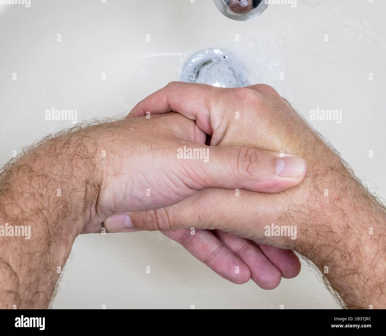 Man washing hands close-up from above, one of several handwashing steps ...