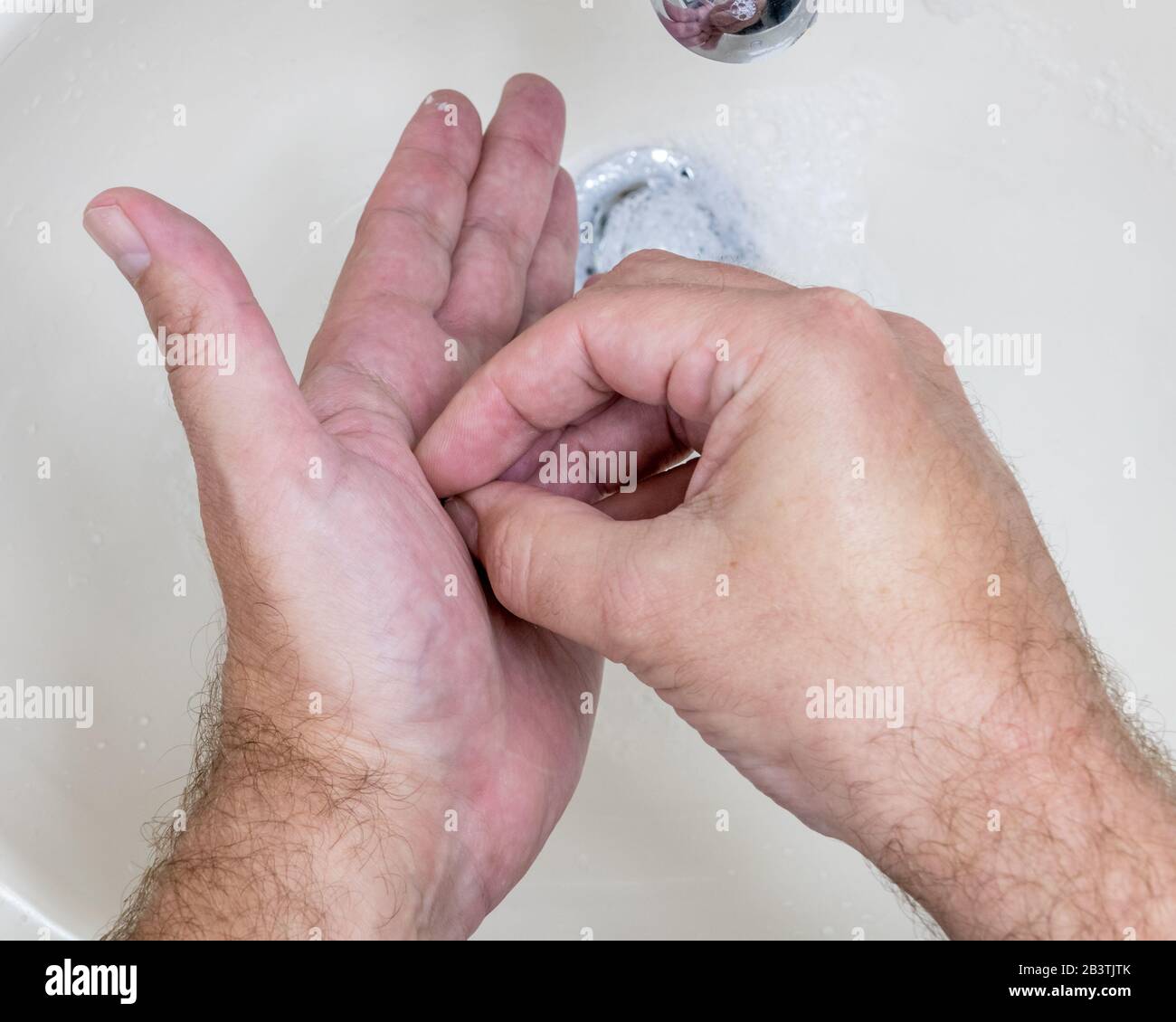 Man washing hands close-up from above, one of several handwashing steps ...