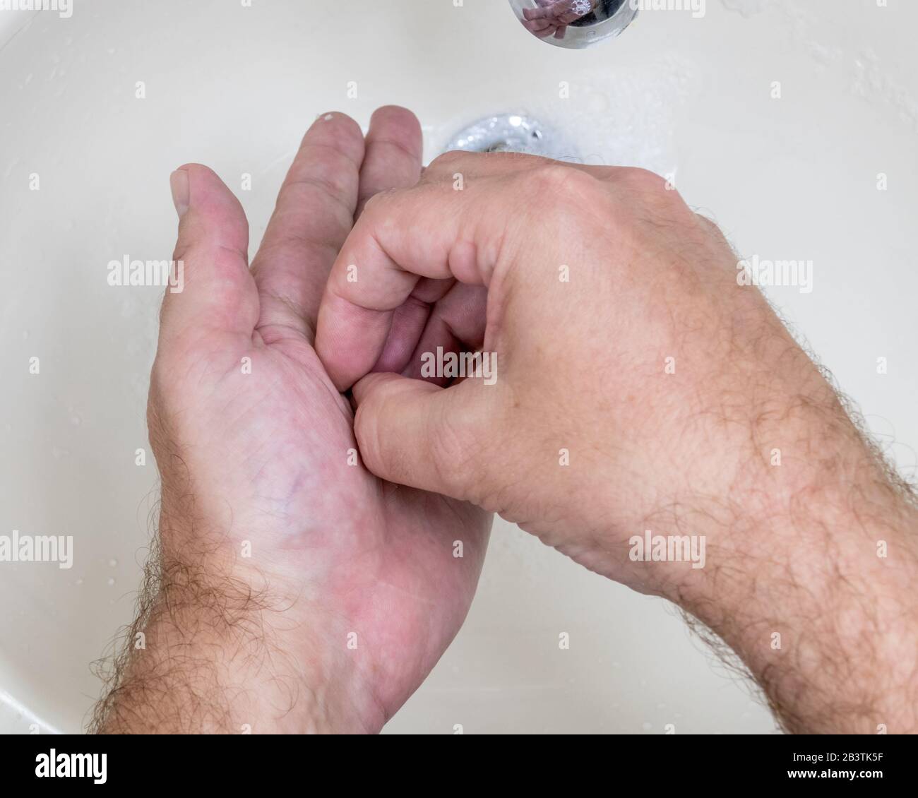Man washing hands close-up from above, one of several handwashing steps ...