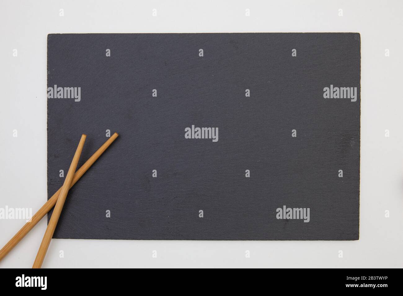 Rectangular slate plate with chopsticks for sushi on the white table ...