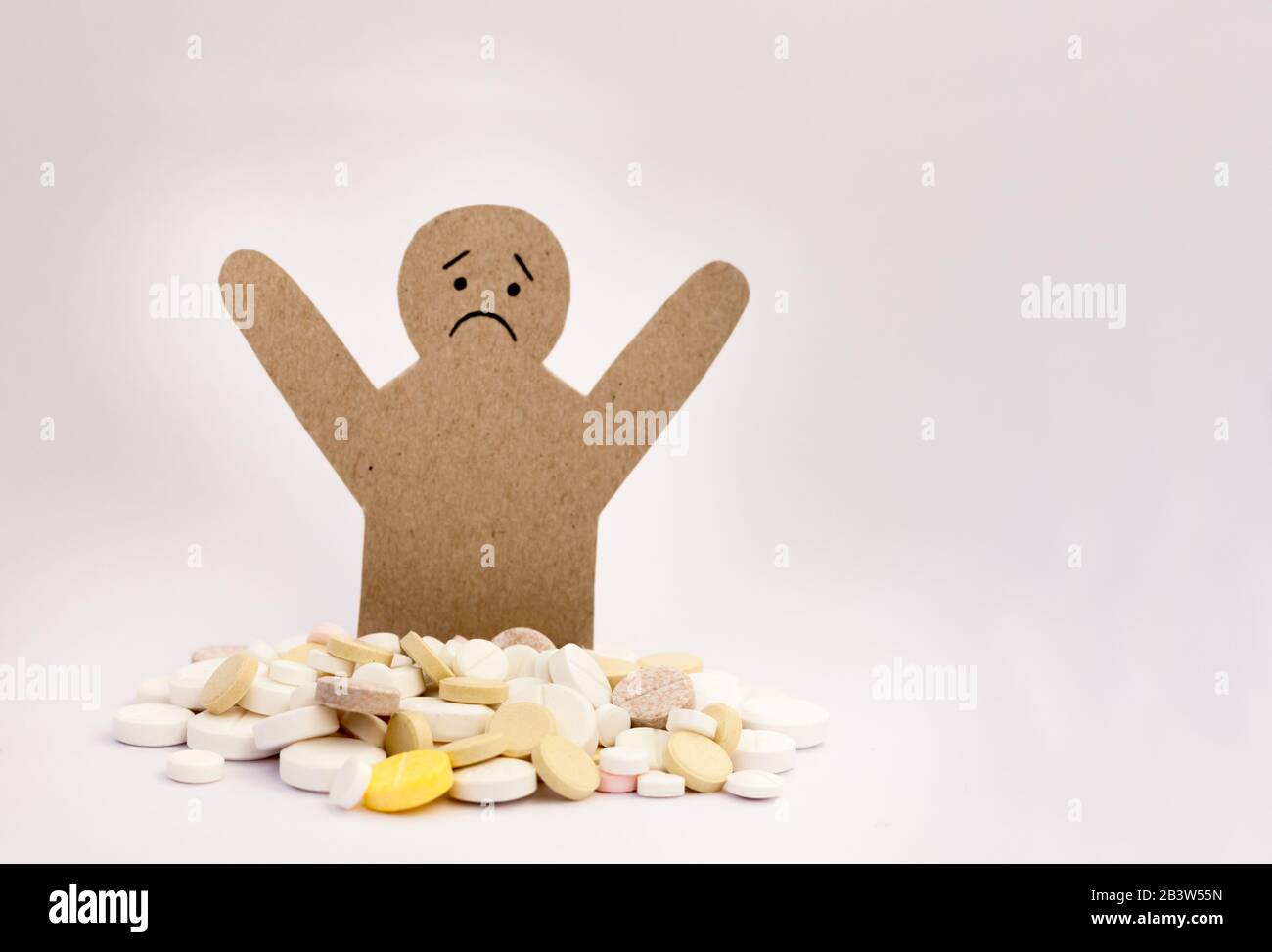 Heap of colorful pills and a figure of a cardboard man, tablets and ...